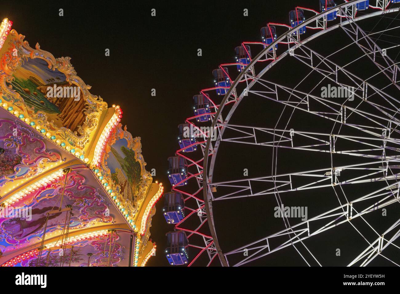 A funfair at night with illuminated chain carousel and Ferris wheel ...