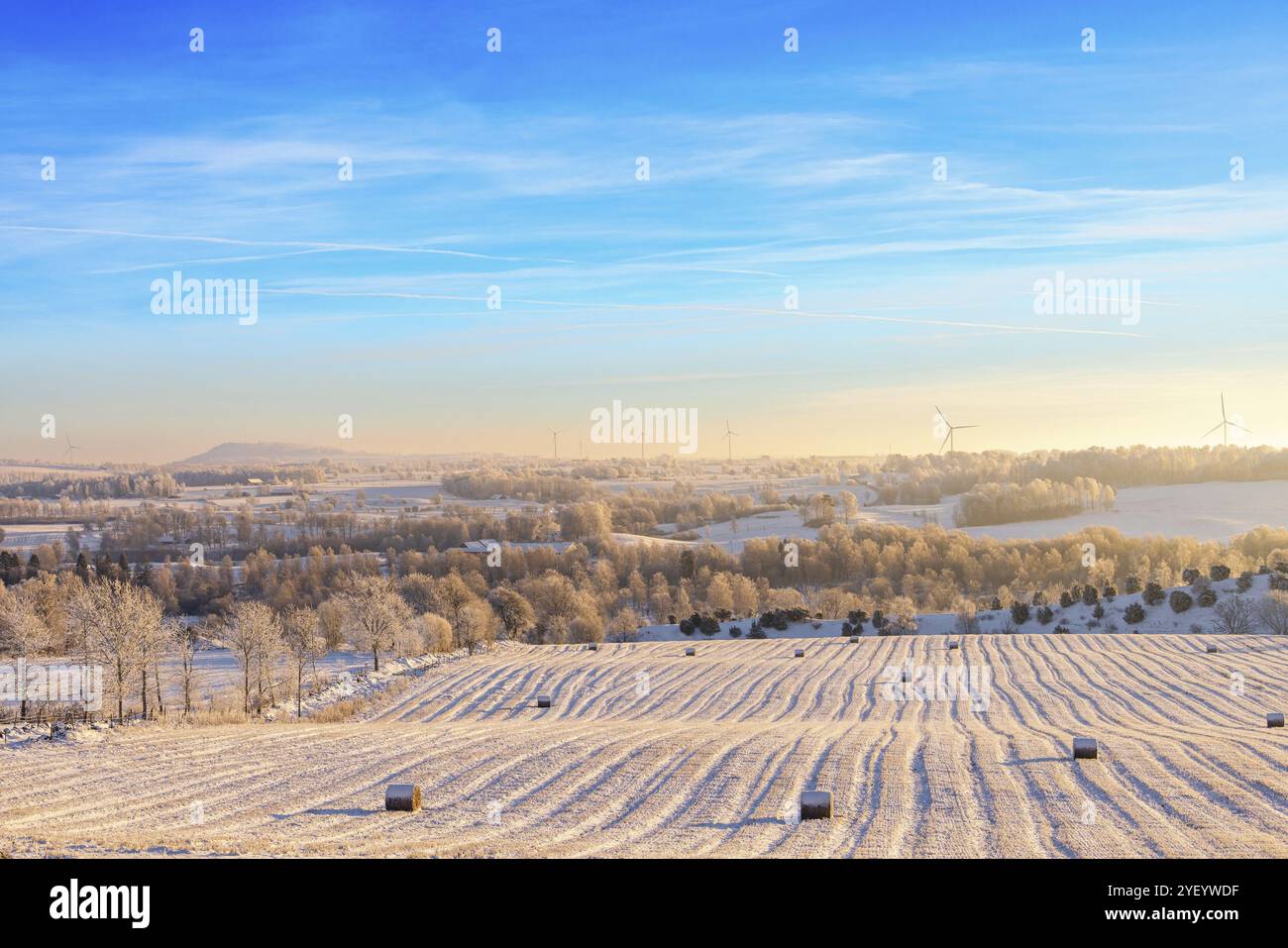 Winter landscape view at a valley with bales on a stubble field in the ...