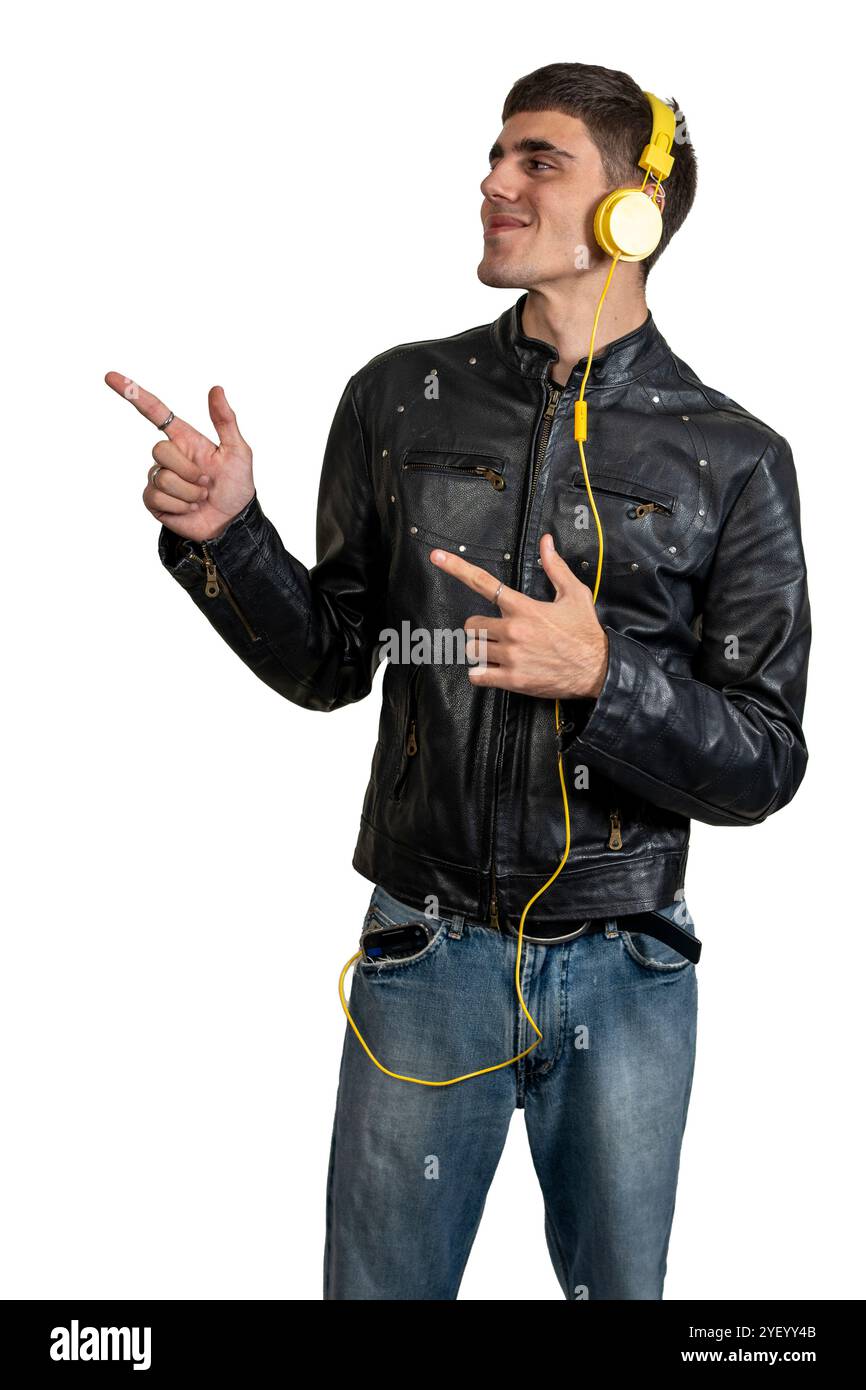 teenage boy listening to music pointing on white background and yellow ...
