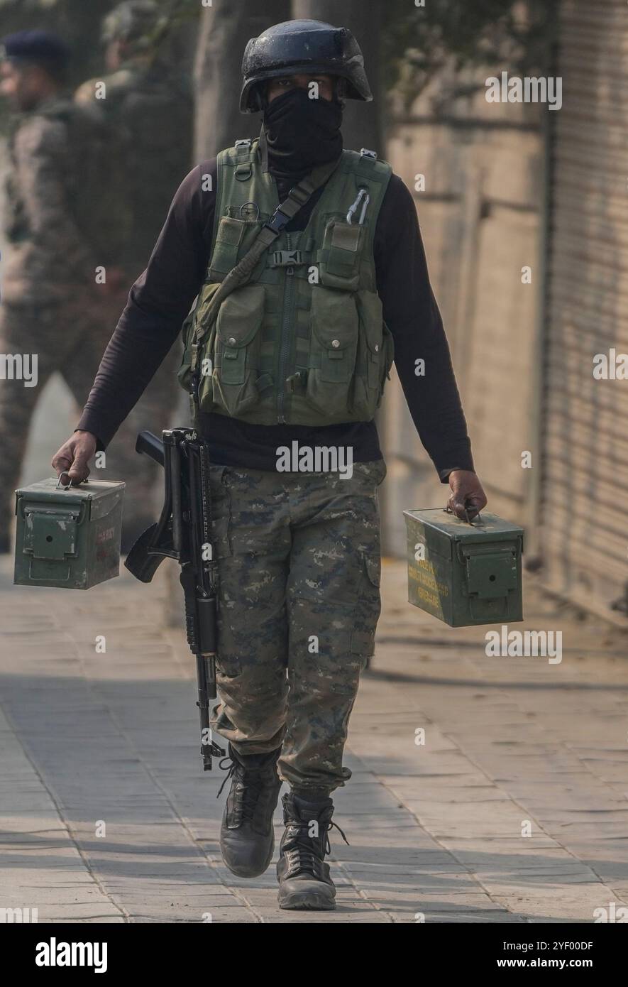 An Indian paramilitary soldier carrying ammunition boxes moves towards ...