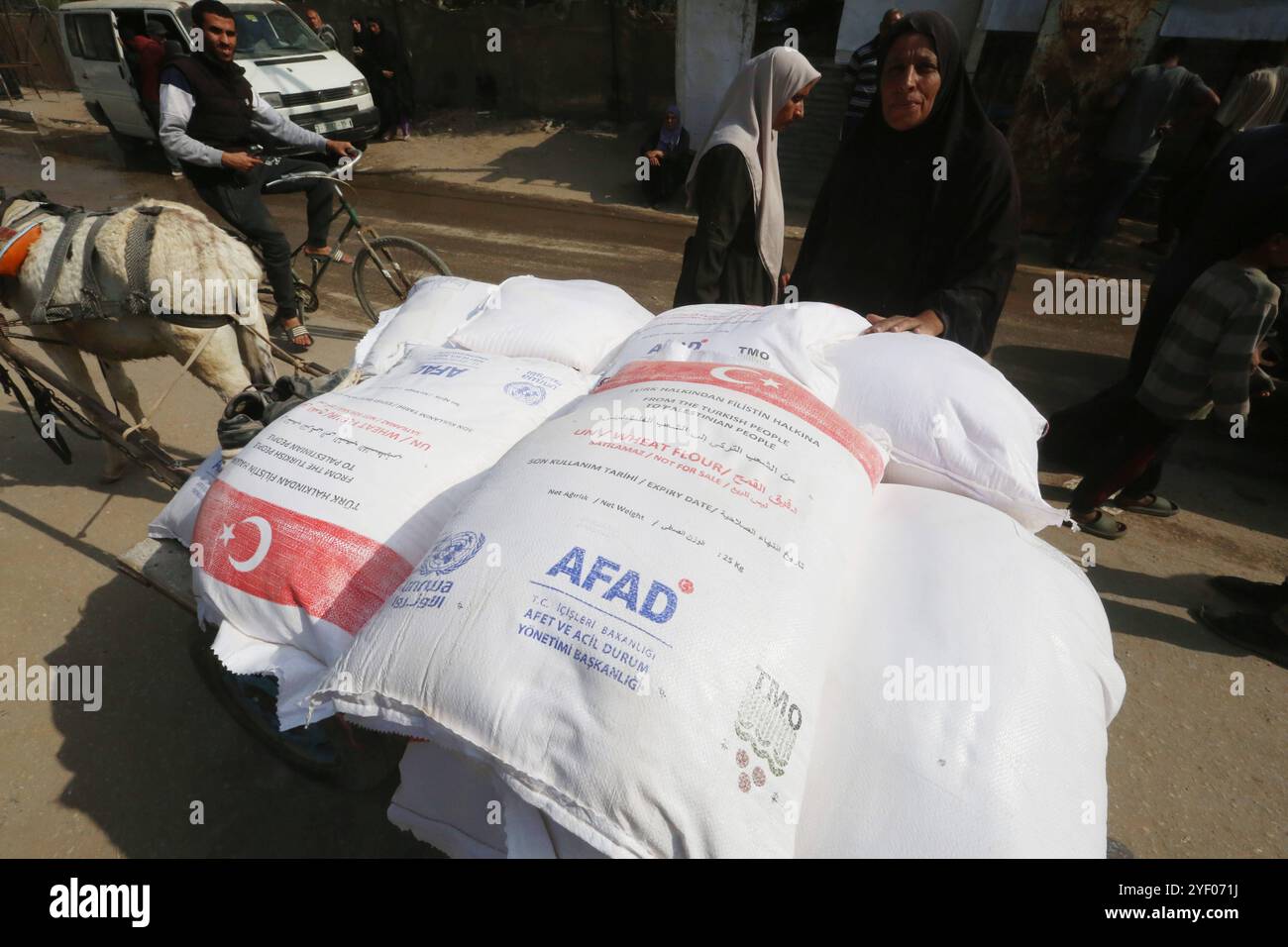Palestinians gather to receive bags of flour handed out by a United ...