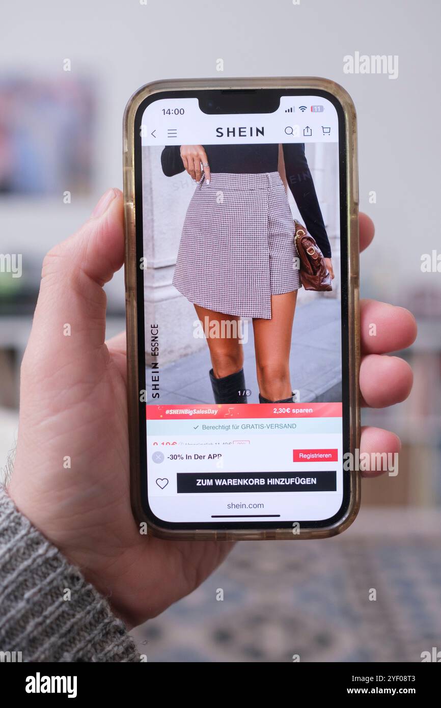 Hand holding a mobile phone showing the website of the Chinese company ...