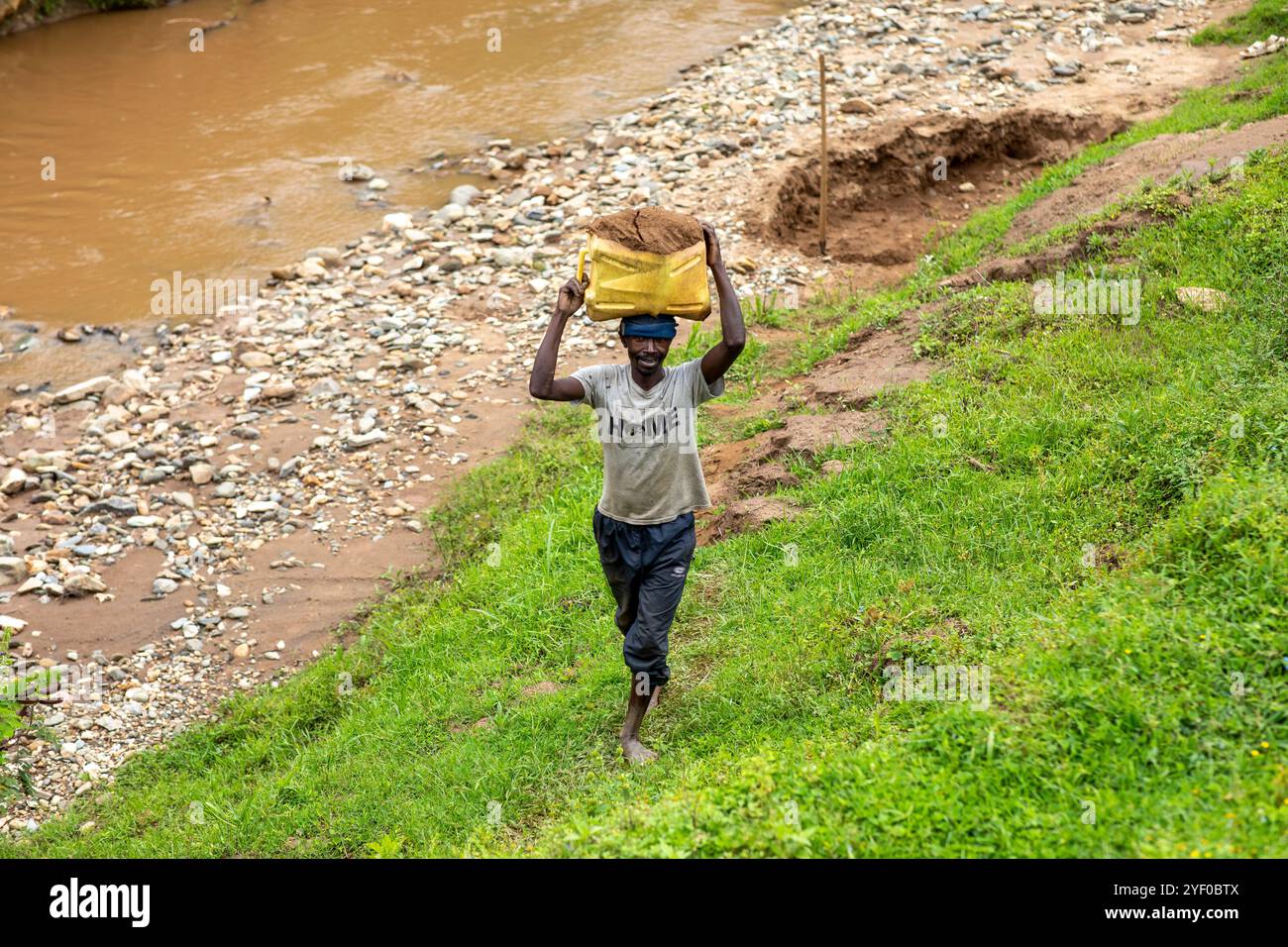 Man carrying mud near a river in western Rwanda Stock Photo - Alamy