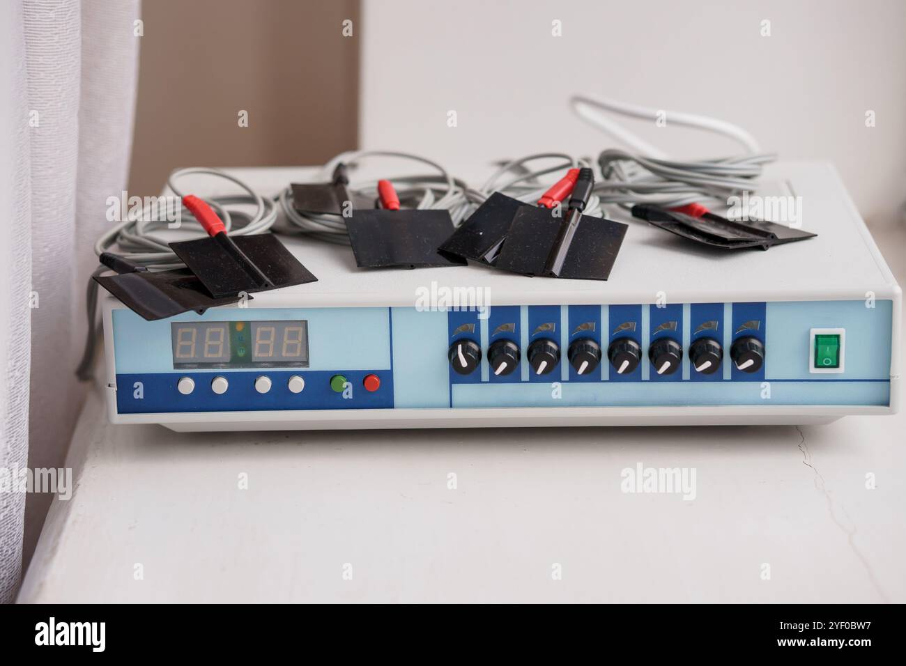 Medical Electrotherapy Device with Electrode Leads on a White Surface ...