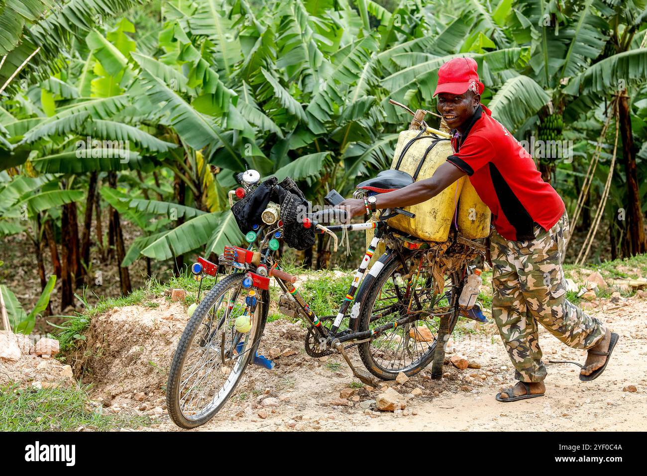 Man pushing a bike loaded with water tanks in western Rwanda Stock ...
