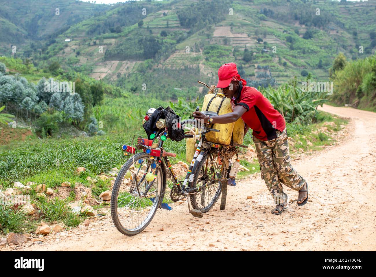 Man pushing a bike loaded with water tanks in western Rwanda Stock ...