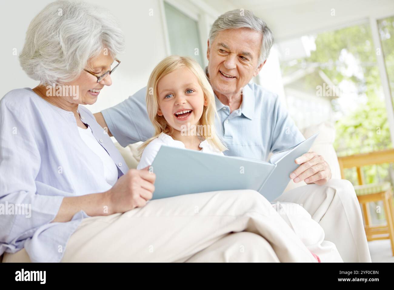 Grandparents, excited and girl reading book in home for learning ...