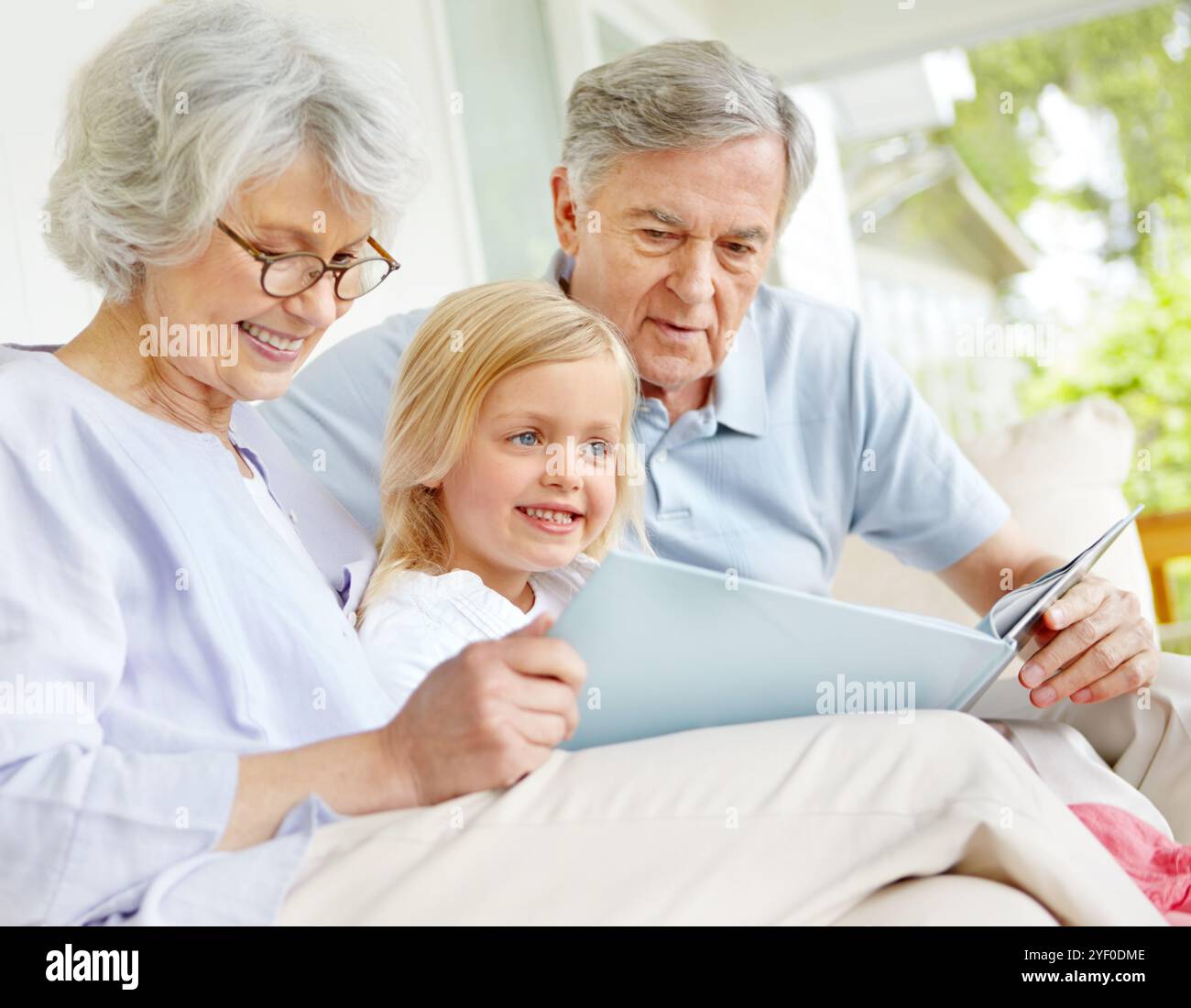 Grandparents, happy and girl reading book in home for learning, bonding ...