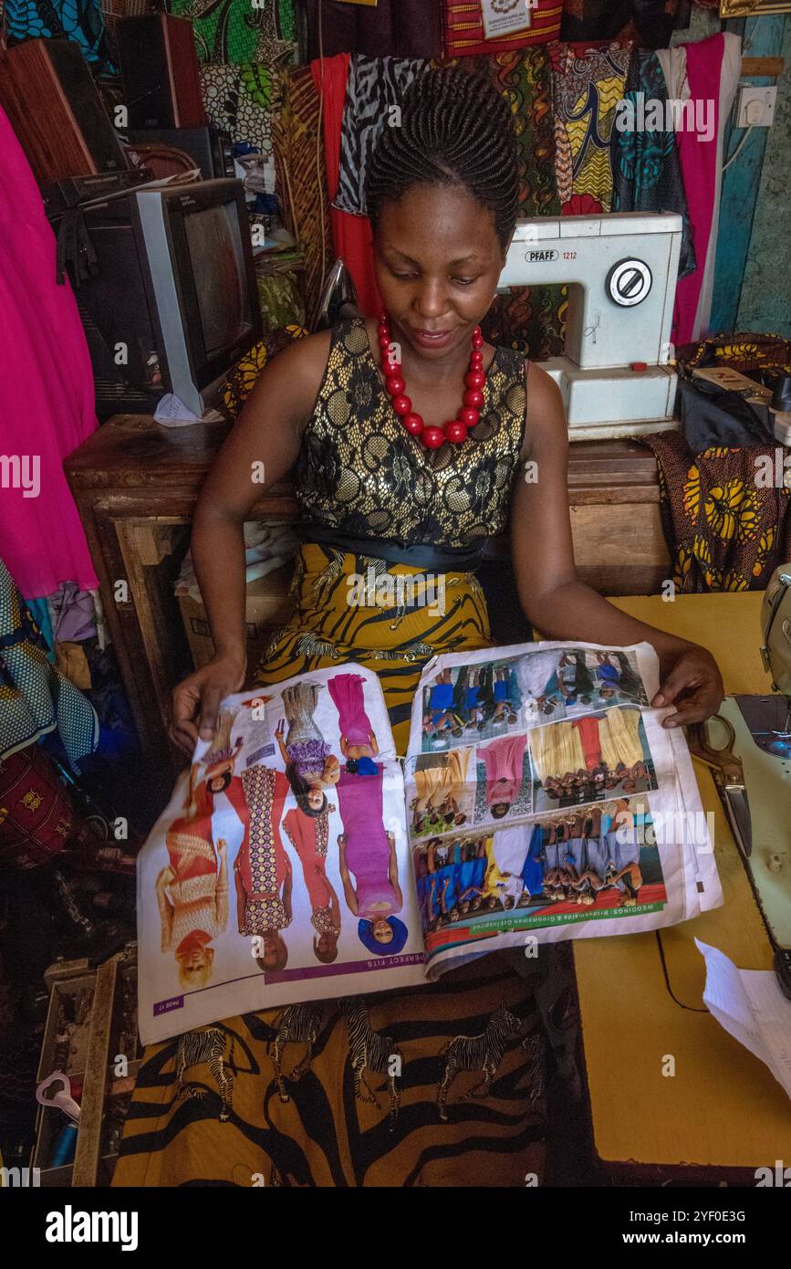 Dressmaker looking at dress models in her stall, Masindi, Uganda Stock ...
