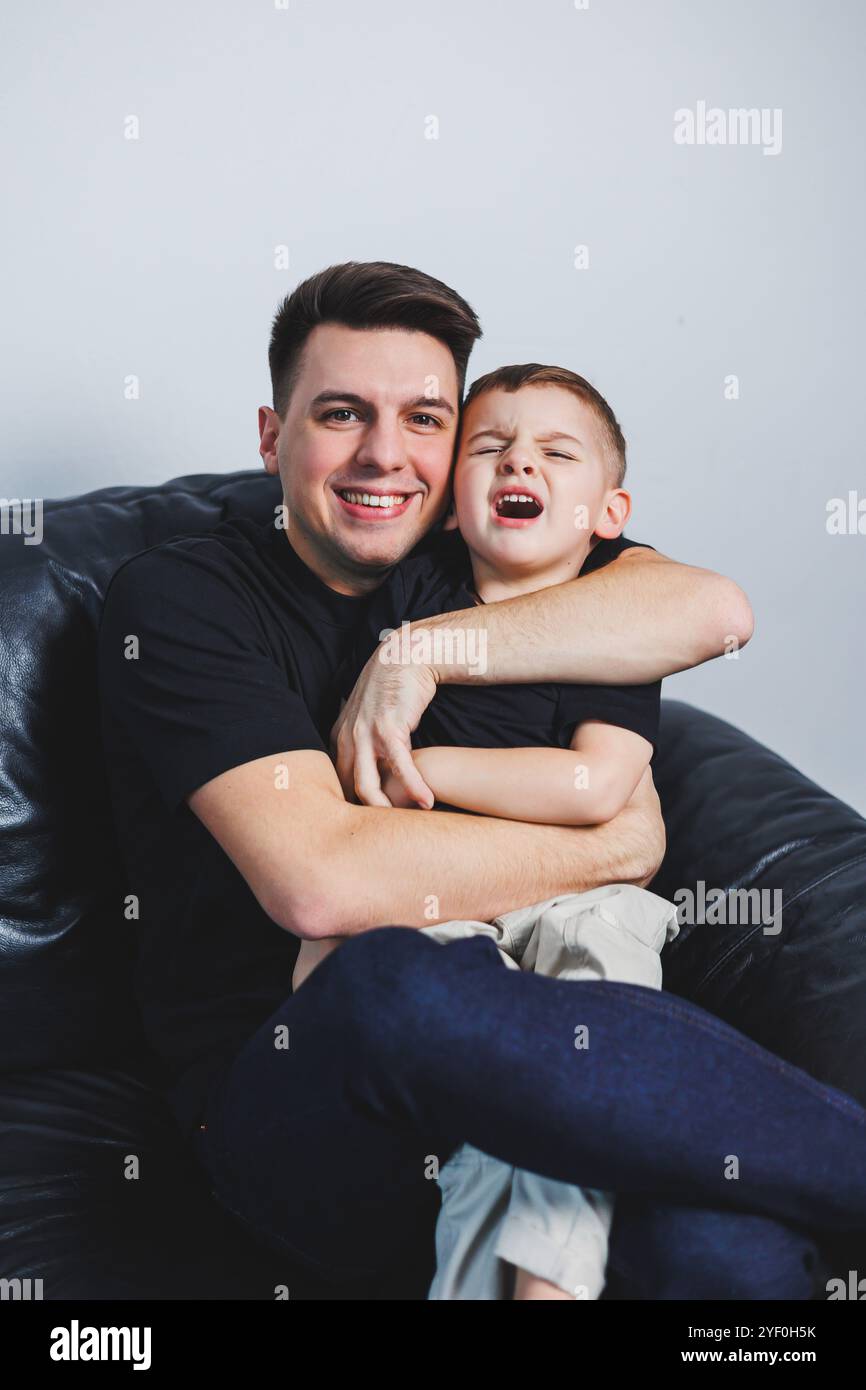 Happy dad hugs his little son while sitting on sofa. A father's love for his son. Family ...