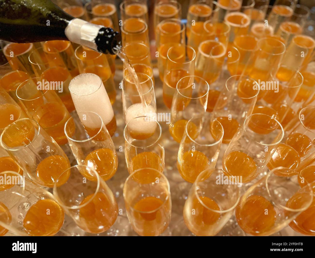 Full frame overhead view of prosecco being poured into glasses with ...