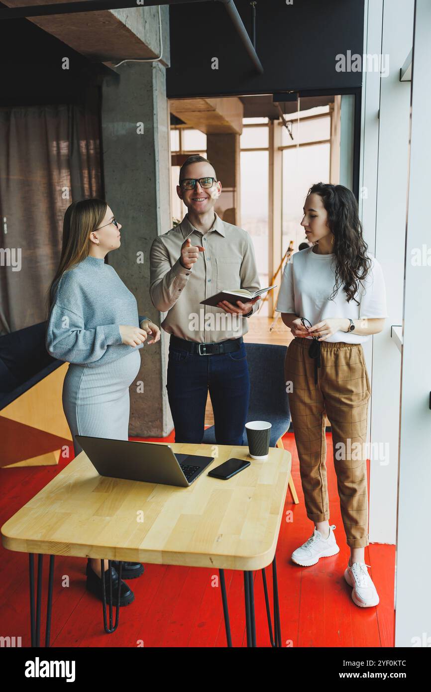 Modern pregnant woman working in office with colleagues. A young ...