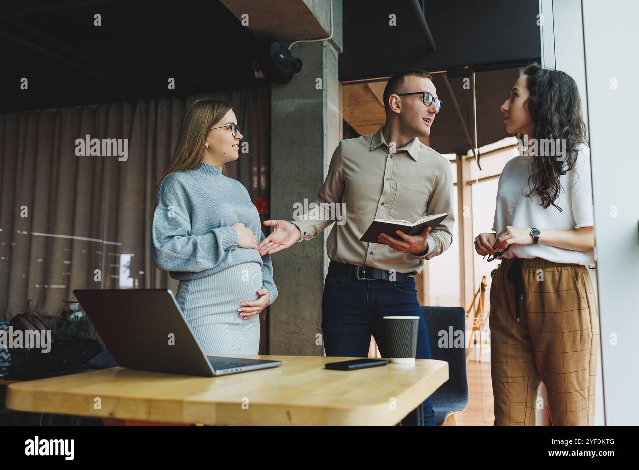 Modern pregnant woman working in office with colleagues. A young ...