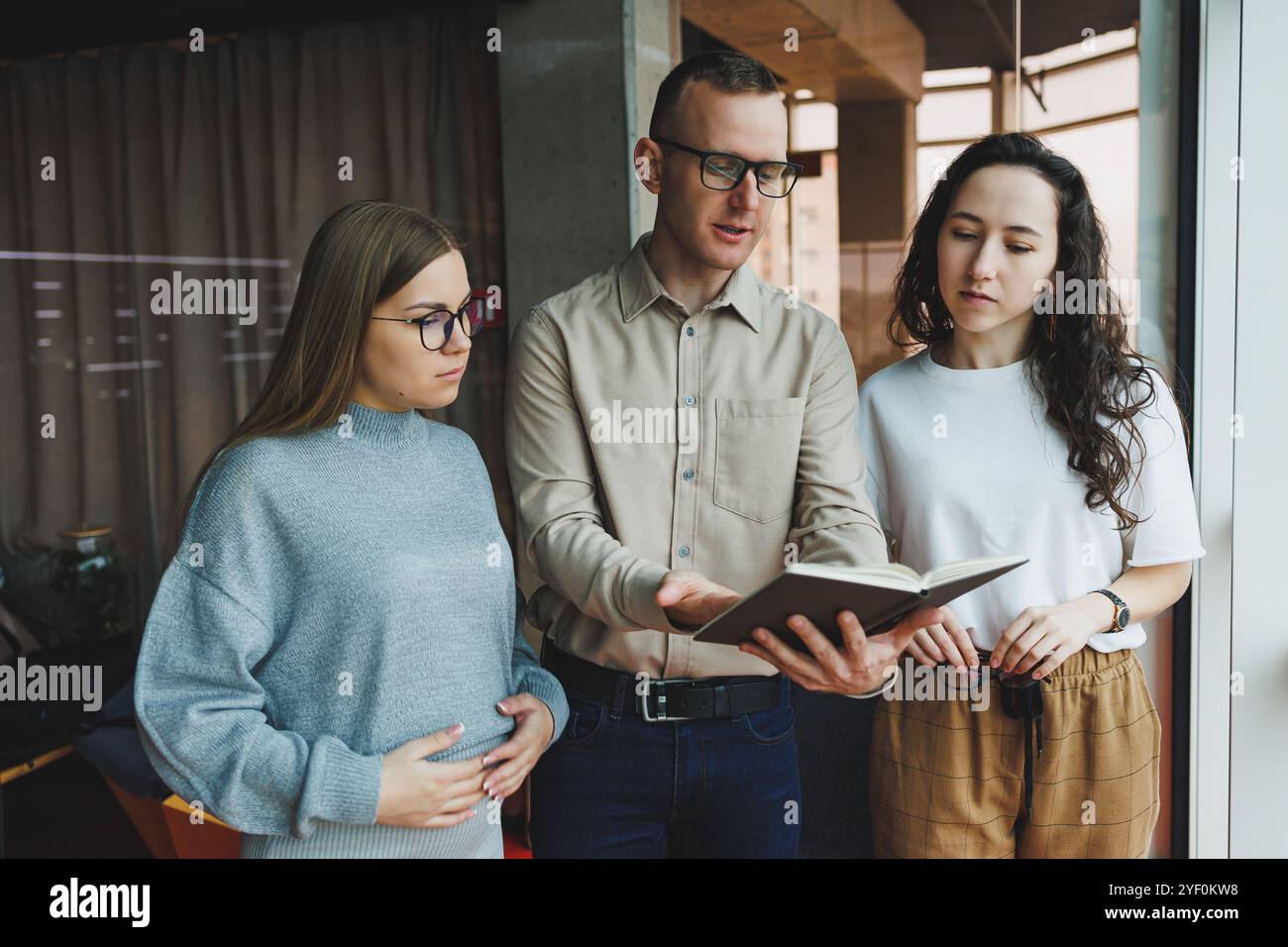 Modern pregnant woman working in office with colleagues. A young ...