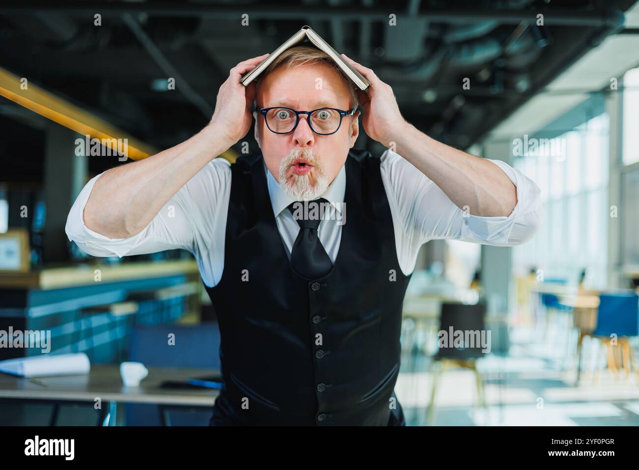 Emotional old man in glasses with a notebook in the office. An old ...