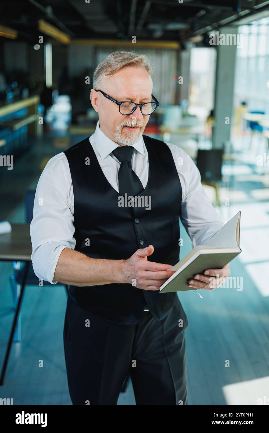 Male financier with gray hair reviewing financial reports and contracts ...