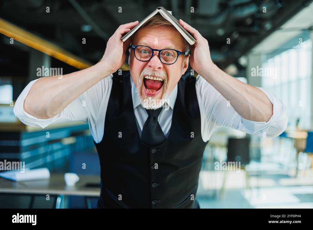 Emotional old man in glasses with a notebook in the office. An old ...