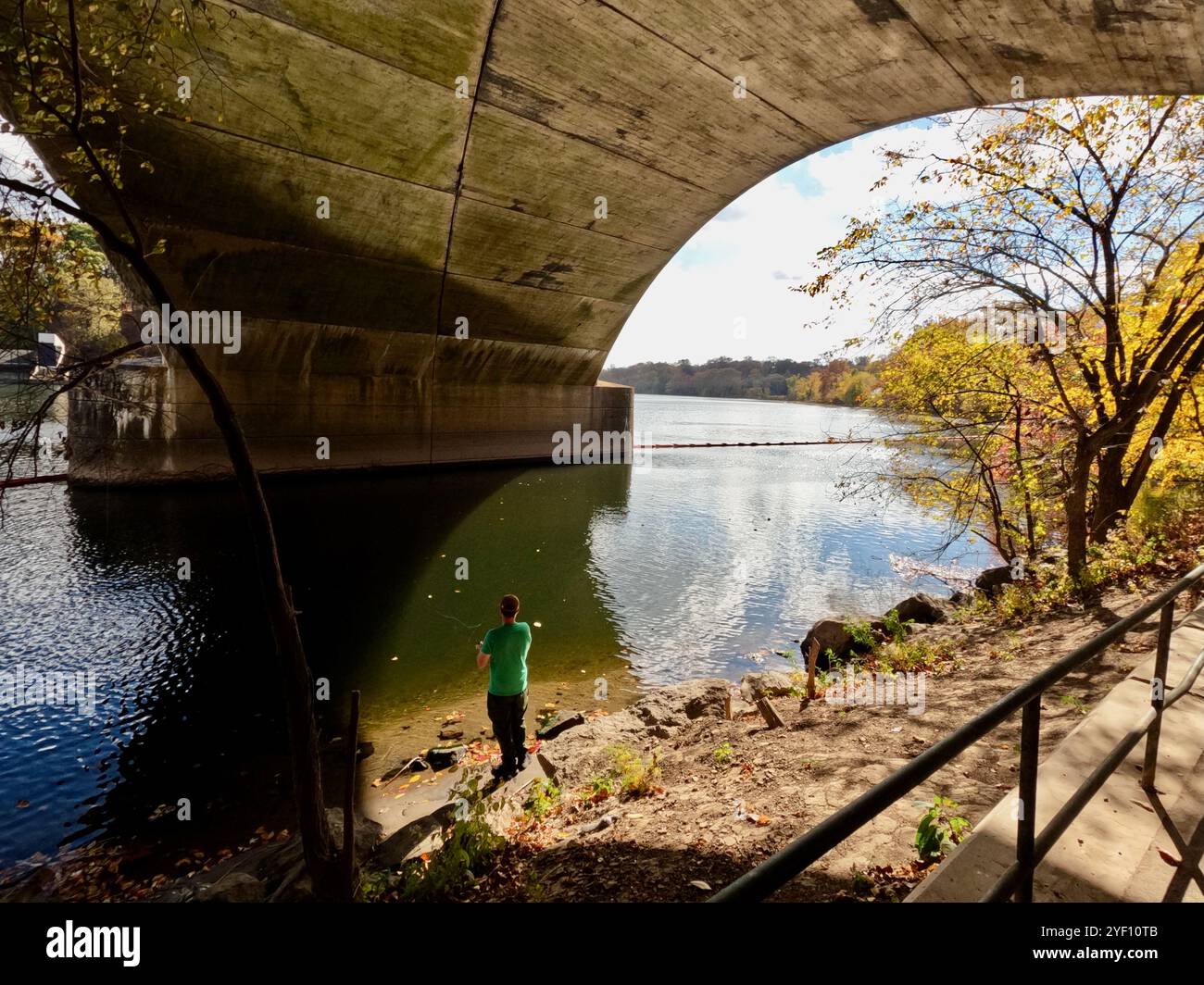 A fisherman plies the Schuylkill River under the Columbia rail bridge ...