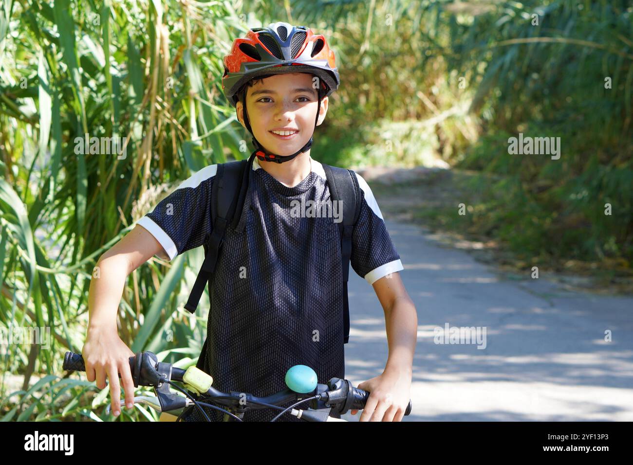 outdoor sport. teenage boy with helmet cycling along a path through ...
