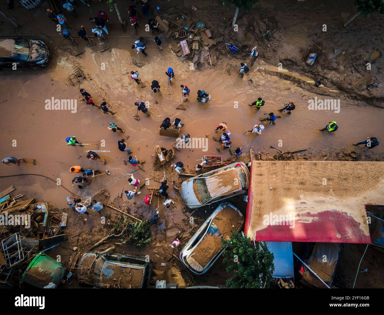 Volunteers and residents clean the mud four days after flash floods ...