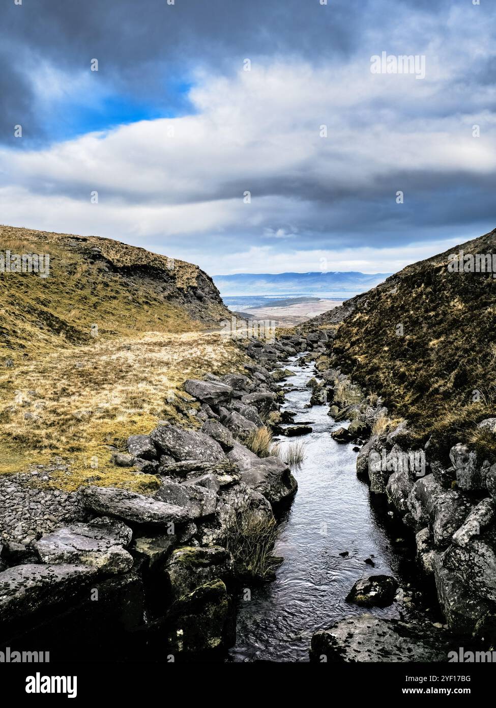 A rocky creek winds its way through a valley, flanked by slopes covered ...