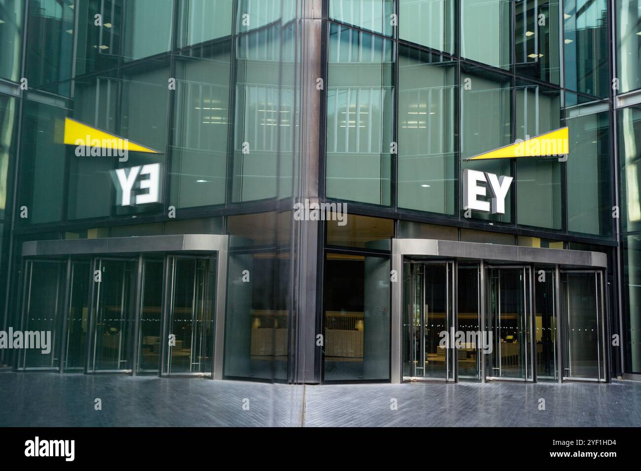A man walks pass the entrance to Financial services firms EY office, white EY lettering and ...