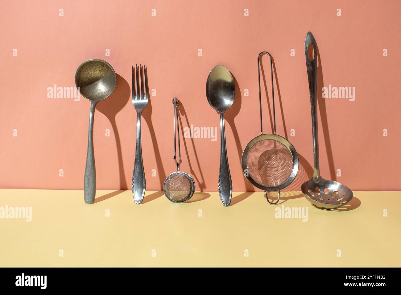 Kitchen utensils arranged in a horizontal row next to the pink wall ...