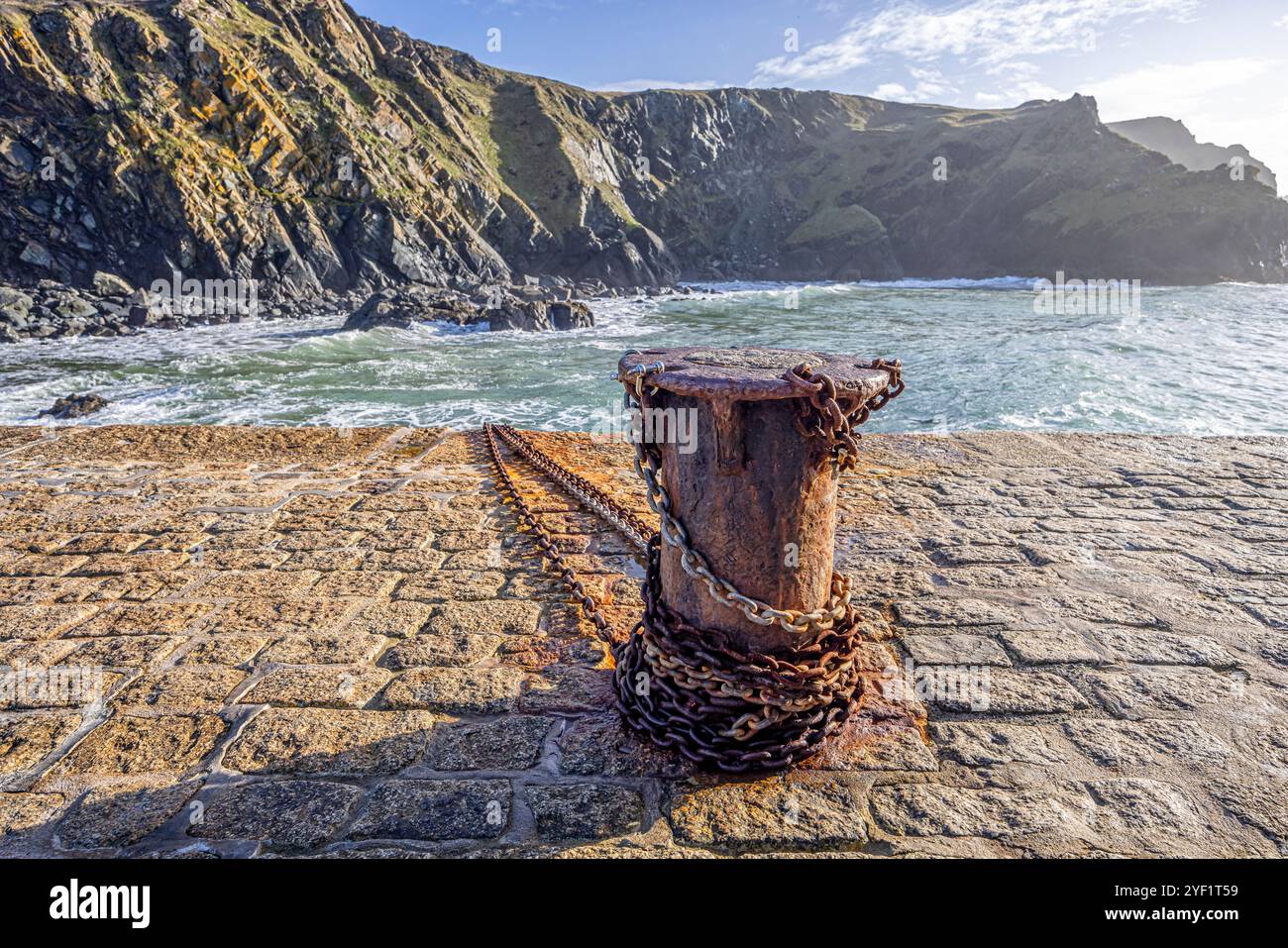 Rusty mooring post on sea wall at rugged Mullion Cove, Cornwall, UK on ...