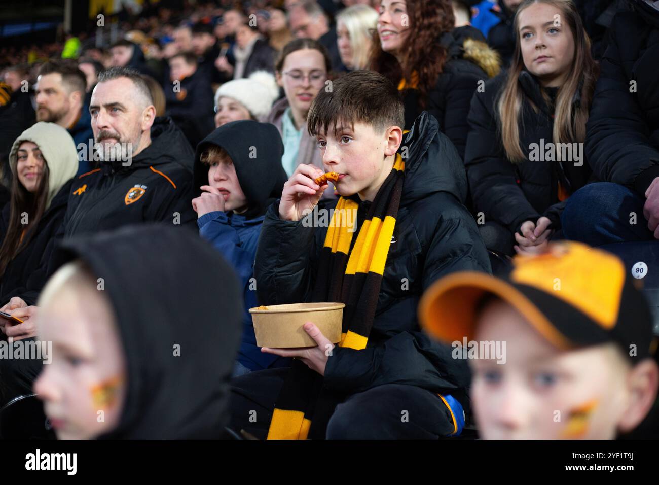 A young fan eating food in the crowd at Hull City football club ( known ...