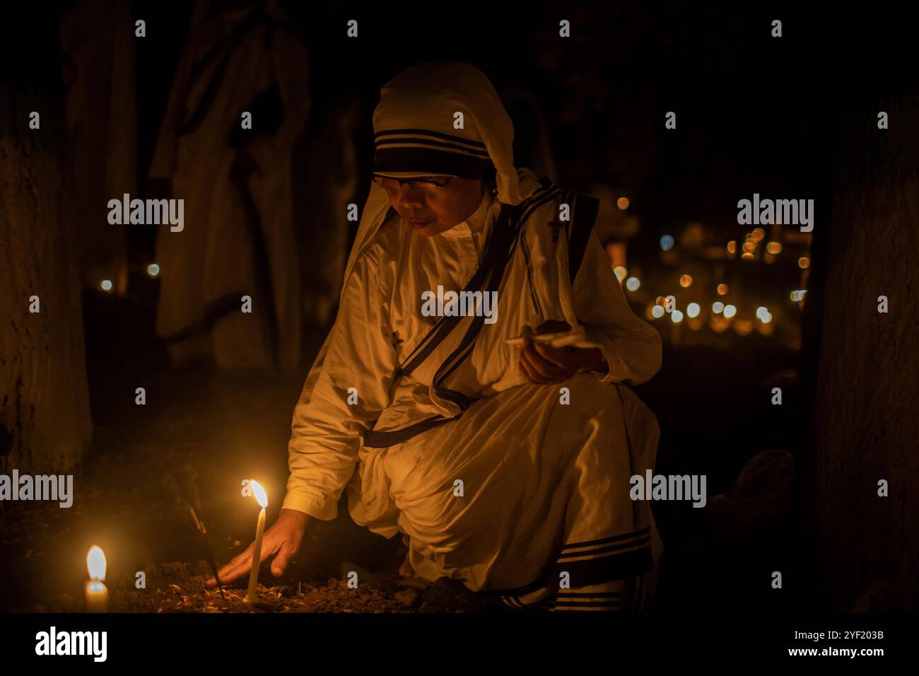 A Christian Nun lights candles in front the grave of his family member ...