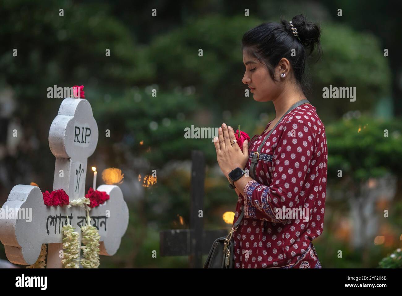A Christian devotee pays respect at the grave of a family member to ...