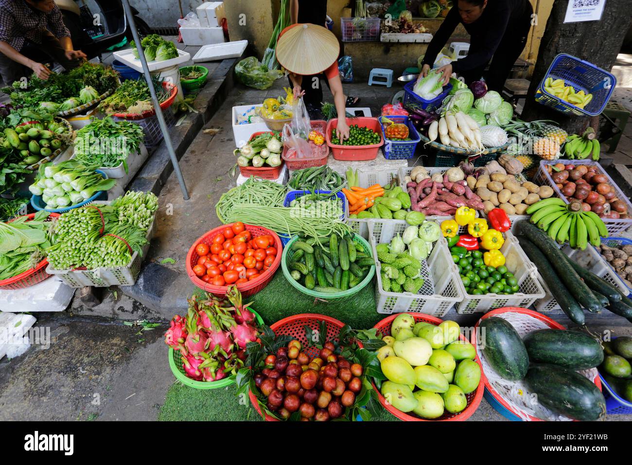 Hanoi, Vietnam - July 14, 2023: Street vendors sell fruits and vegetables at an open air market ...