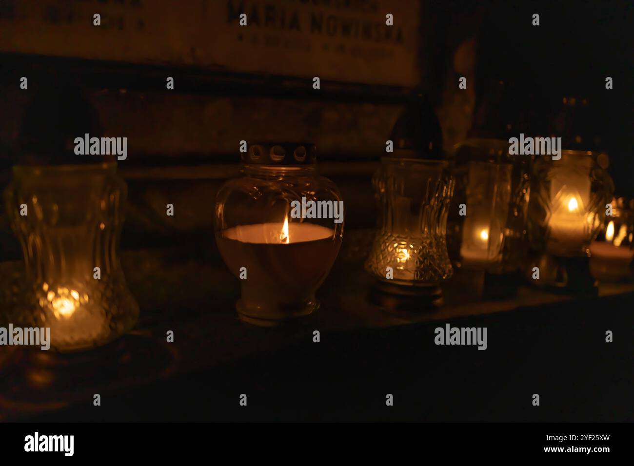 Candle lights on graves and tombstones at a cemetery in Poland during All Saints Day, Zaduszki ...