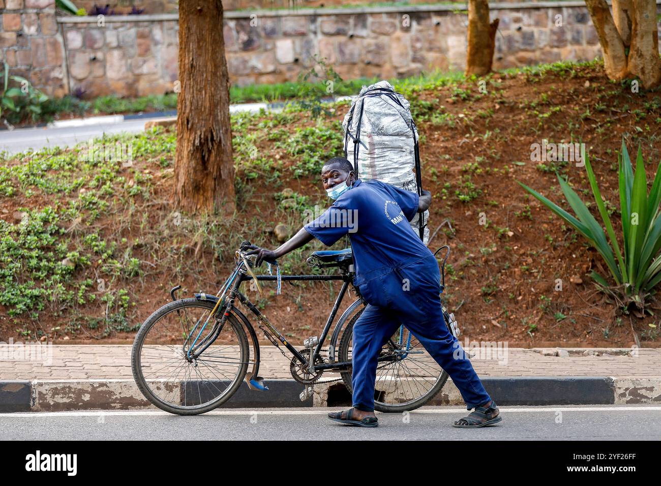 Man pushing a bike loaded with a big bag in Kigali, Rwanda Effort ...