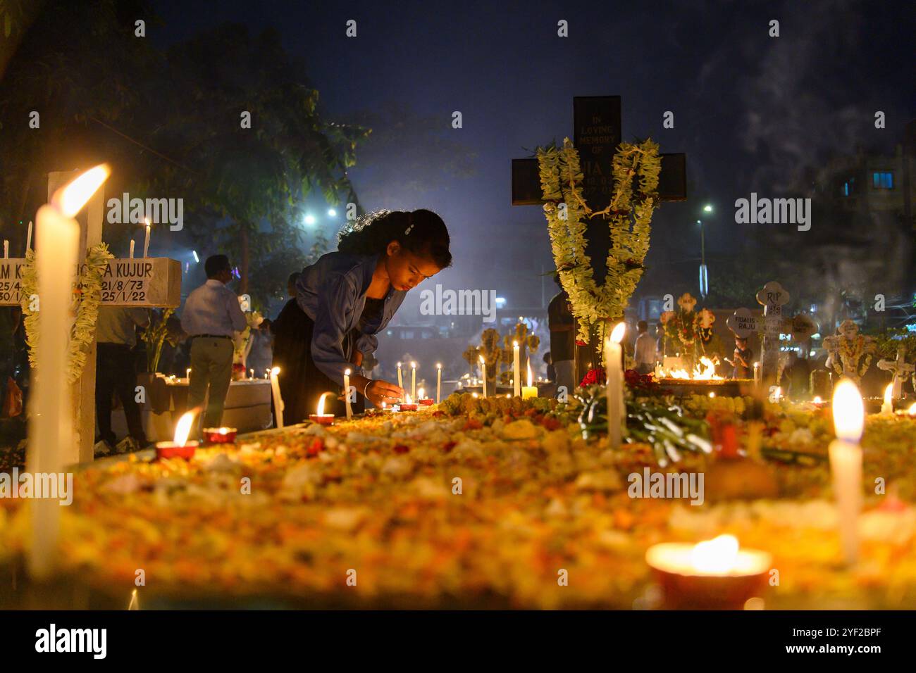 Kolkata, India. 02nd Nov, 2024. A girl lights candles at the graveyard ...