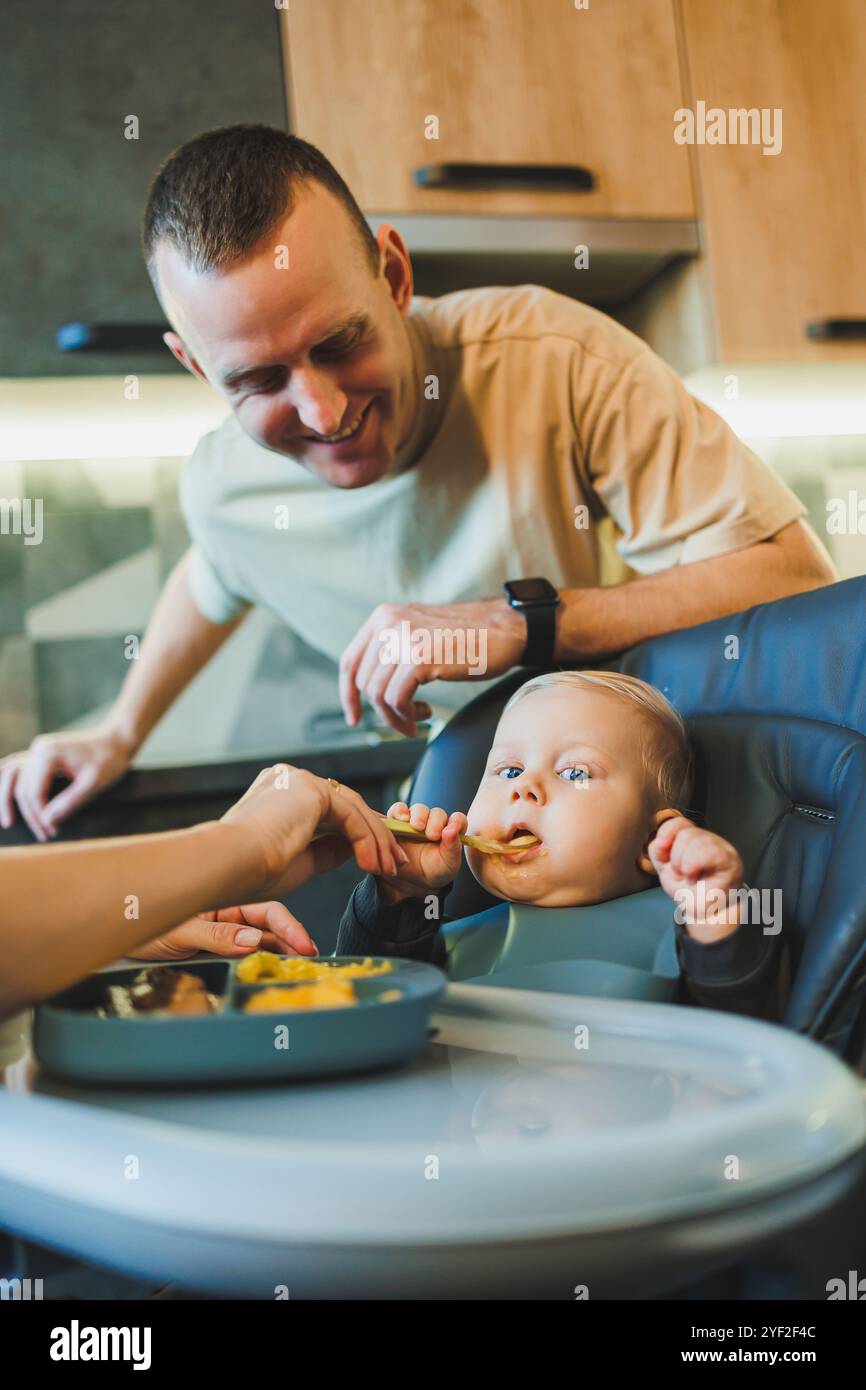 The first complementary food for a baby. A mother feeds puree to her 6 ...