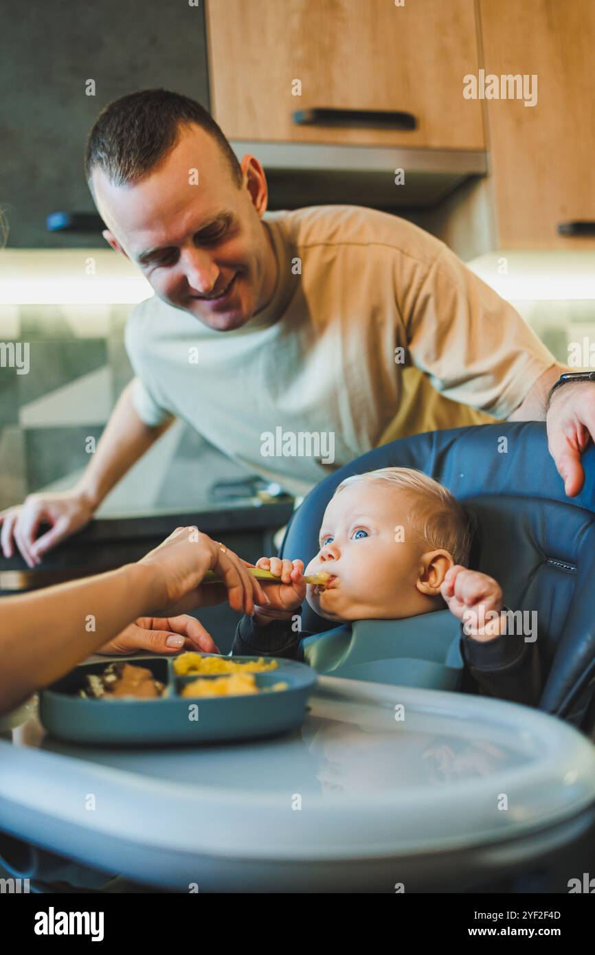 The first complementary food for a baby. A mother feeds puree to her 6 ...