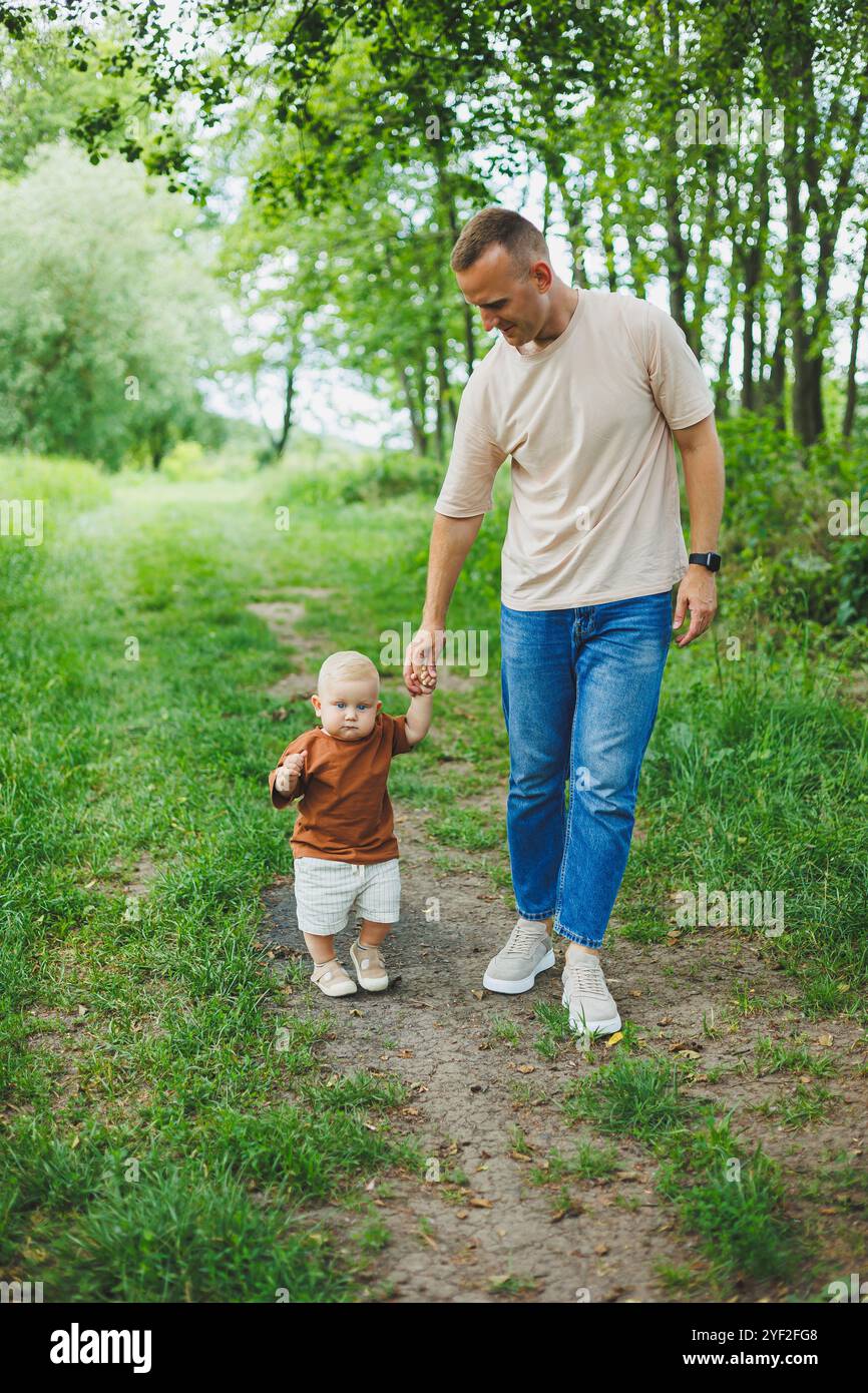 A young father teaches his son to take his first steps. Dad and son on ...
