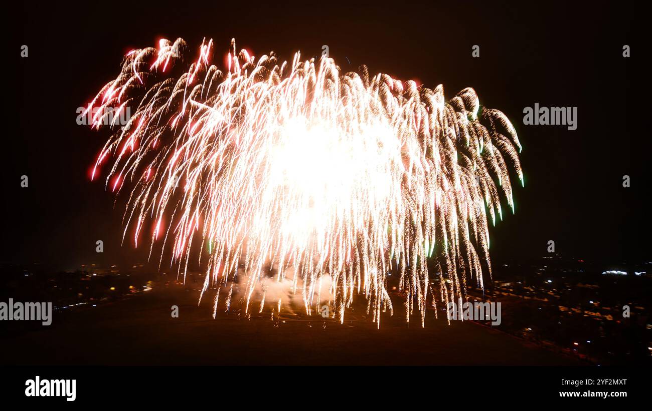 Fireworks explode in the night sky, creating a large, bright display of ...