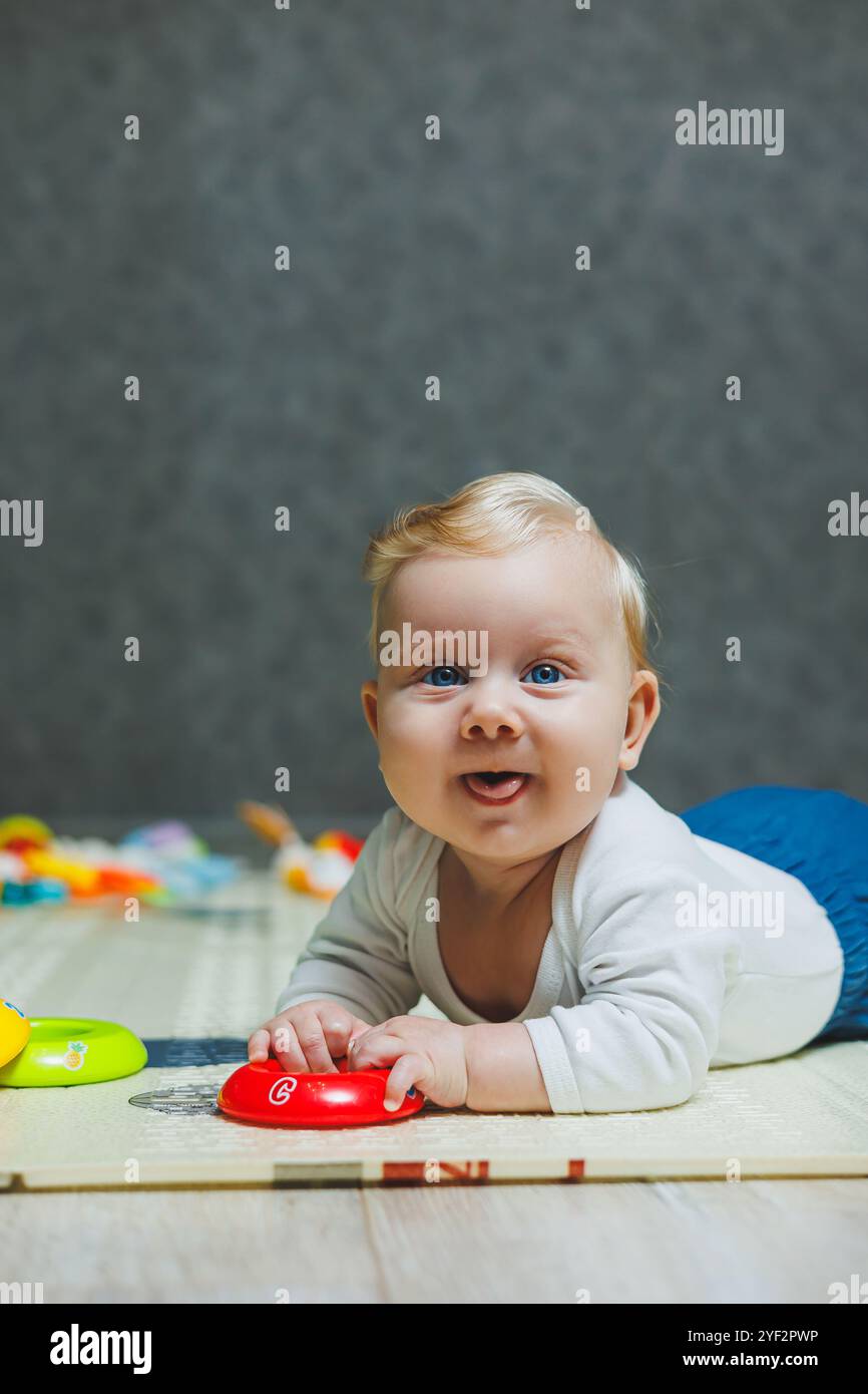 A 5-month-old baby is smiling and lying on a developmental mat. Self ...