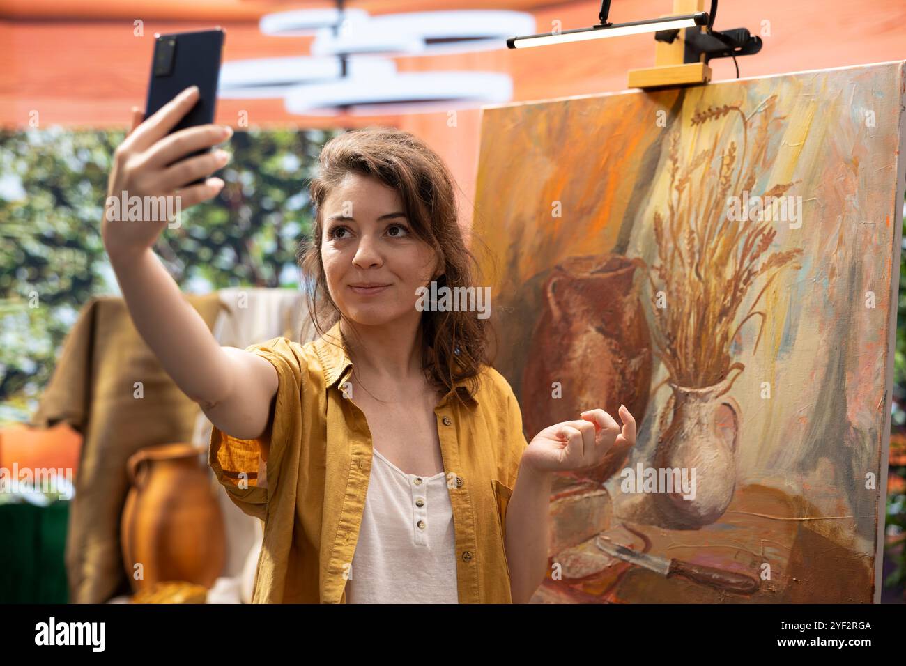 Female artist filming finished rustic artwork for online branding ...