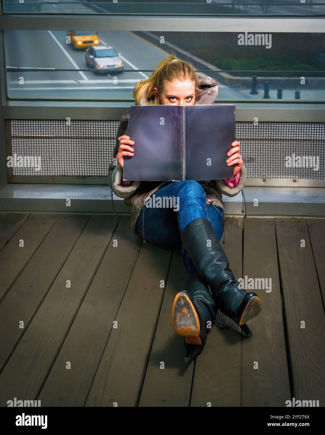 A woman sits on a wooden floor, partially hiding behind a large open ...