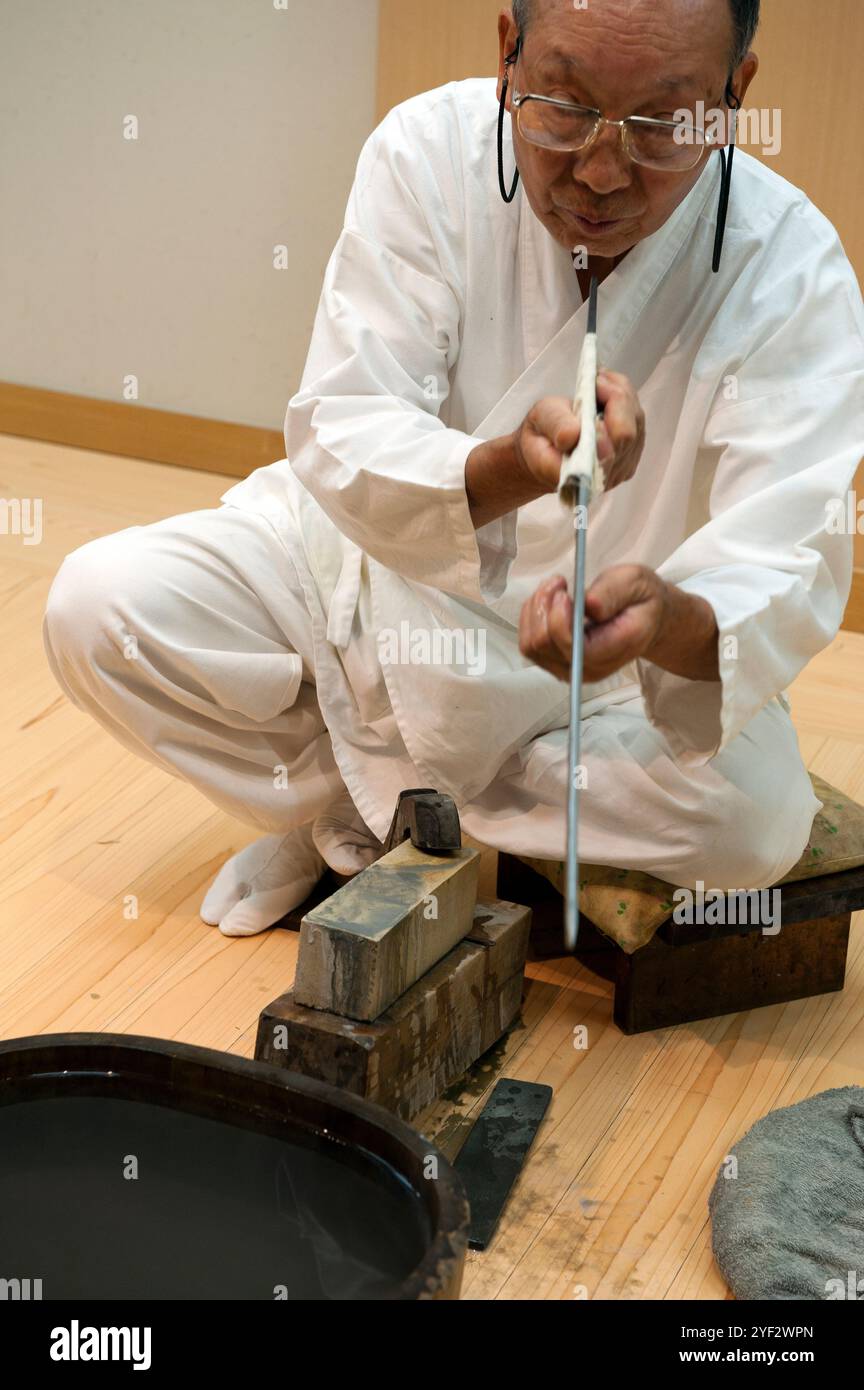 Man sharpening a short Japanese sword called a "wakizashi" in the ...