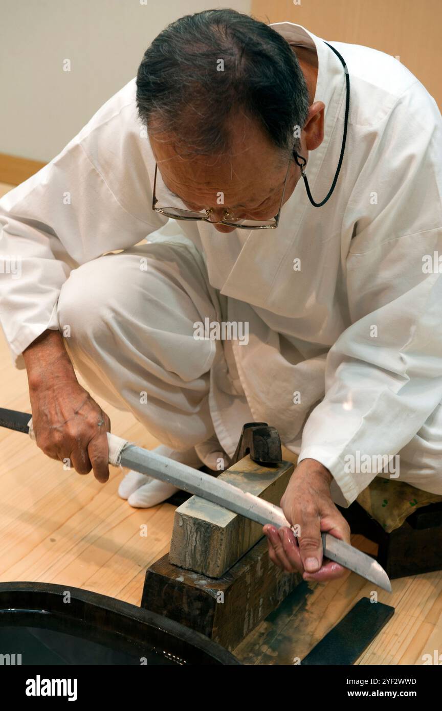 Man sharpening a short Japanese sword called a "wakizashi" in the ...