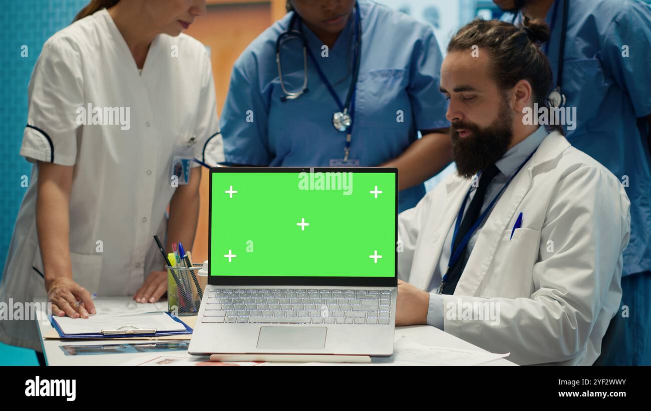 Team of doctors consulting analytics next to green screen on laptop in ...