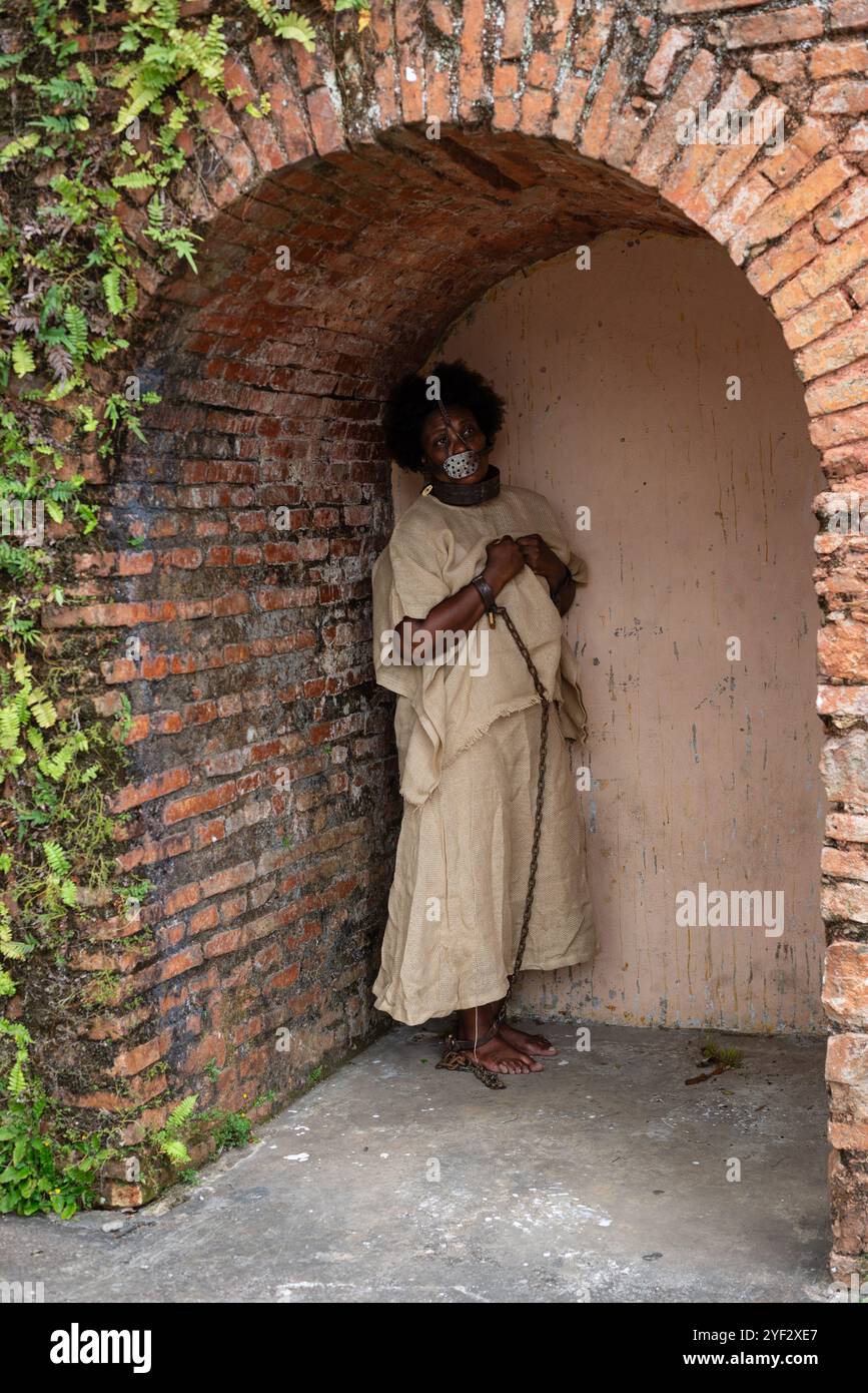 Black woman chained and with an iron mask on her face leaning against a ...