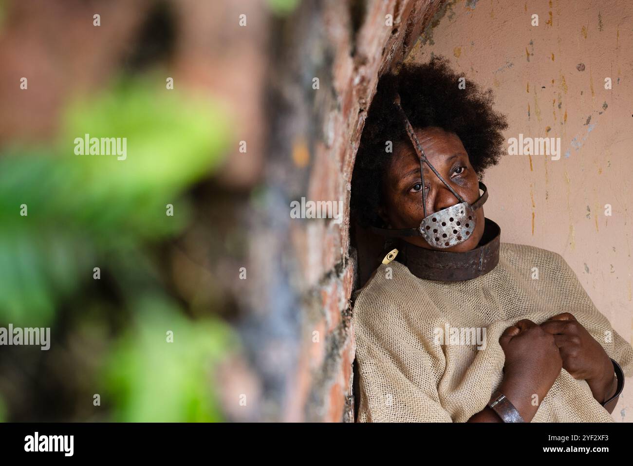 Black woman chained and with an iron mask on her face leaning against a ...
