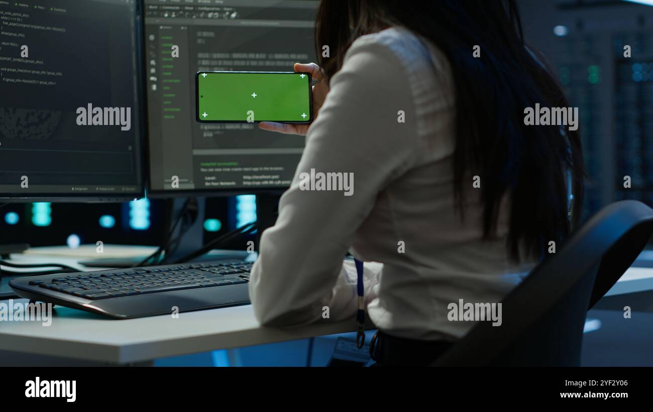 Zoom in on green screen mobile phone used by data center employee troubleshooting issues ...