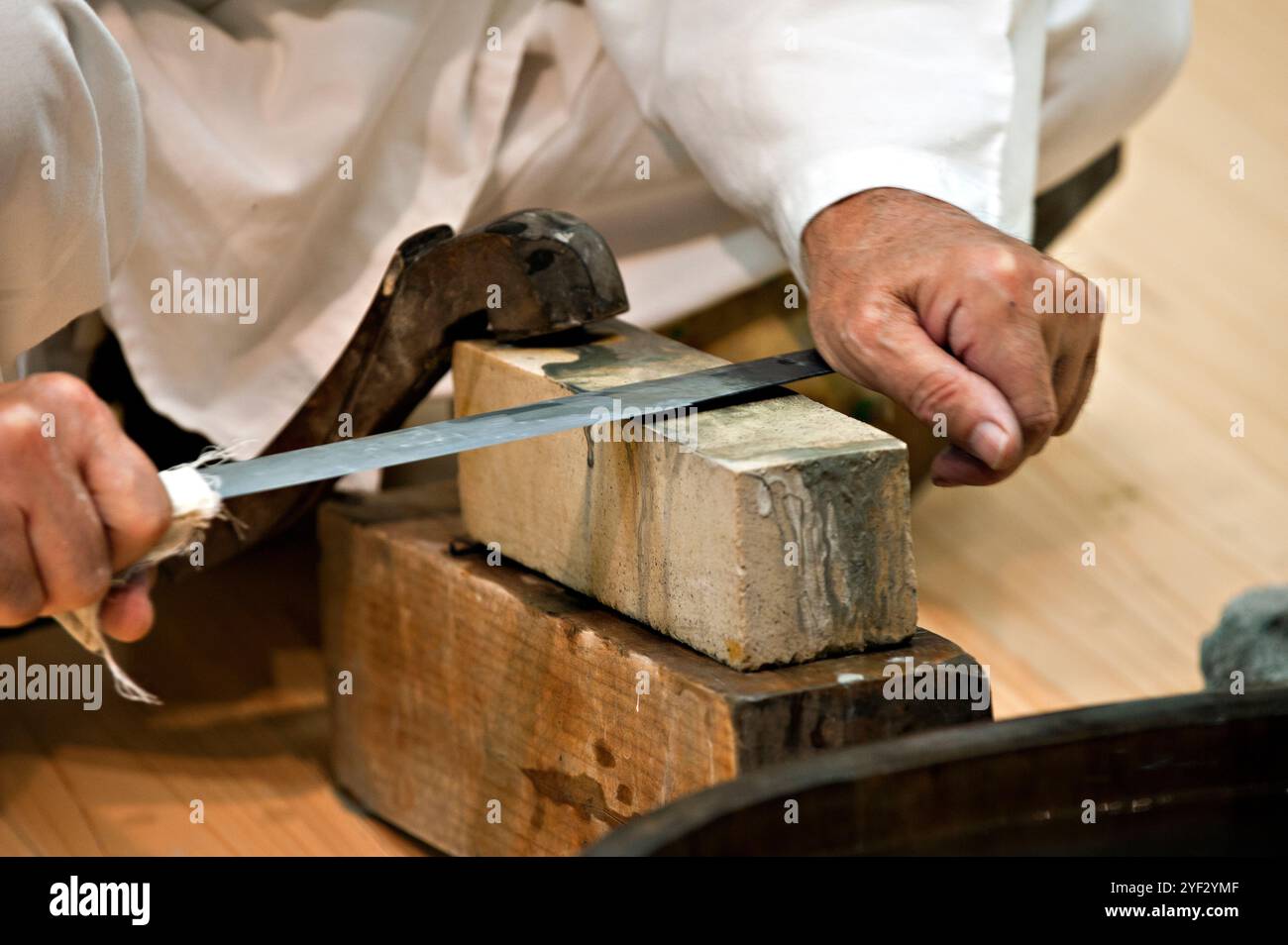Man sharpening a short Japanese sword called a "wakizashi" in the ...