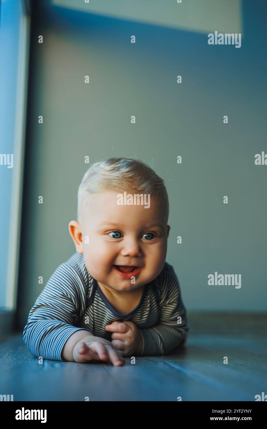Portrait of a small baby boy in a cotton bodysuit with a smile on his ...